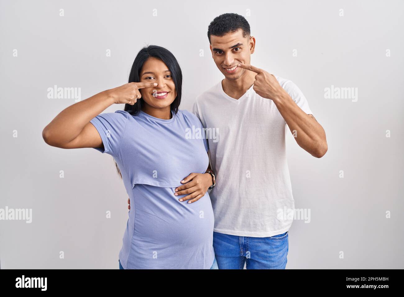 Young hispanic couple expecting a baby standing over background ...