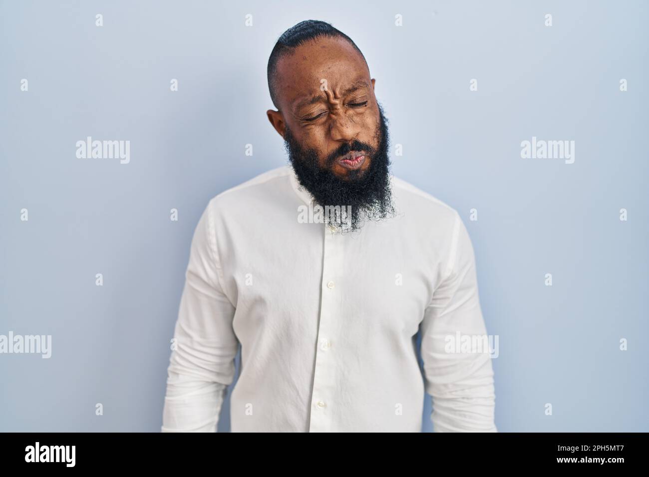 African american man standing over blue background puffing cheeks with ...