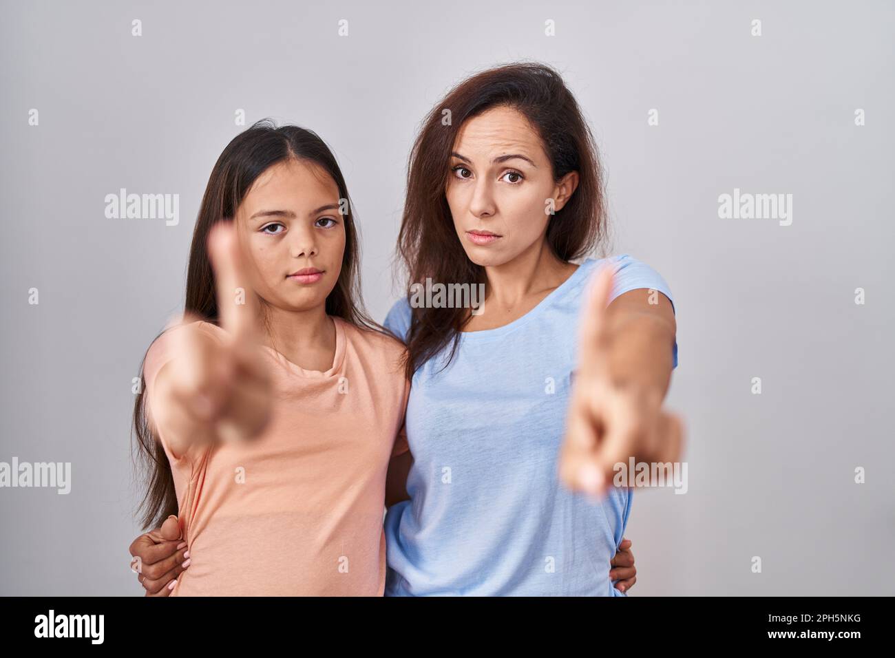 Young mother and daughter standing over white background pointing with ...
