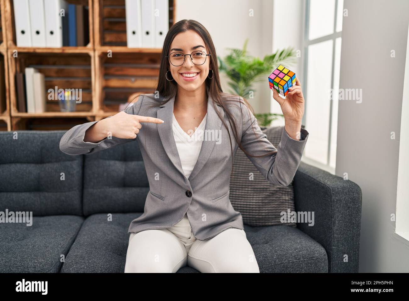 Hispanic woman playing colorful puzzle cube intelligence game pointing ...