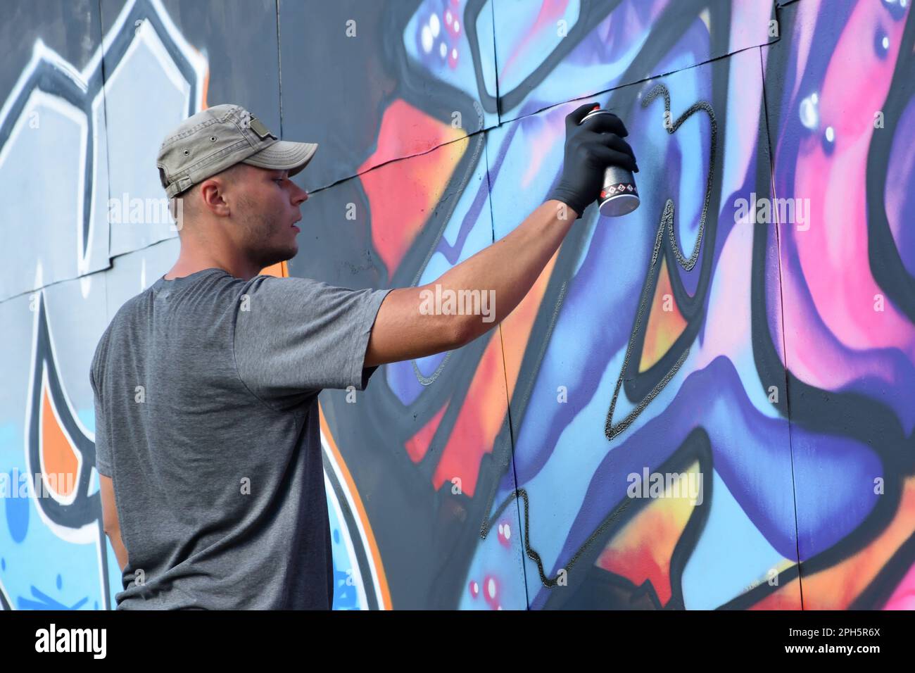 Young caucasian male graffiti artist drawing big street art painting in ...