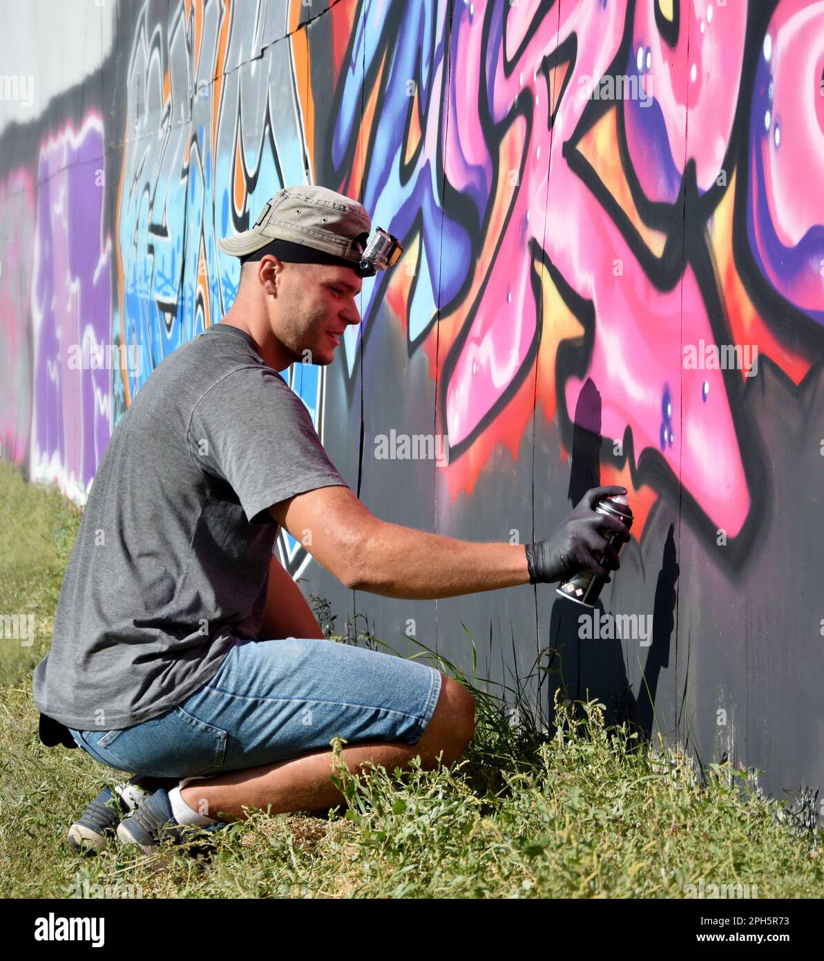 Young caucasian male graffiti artist drawing big street art painting in ...