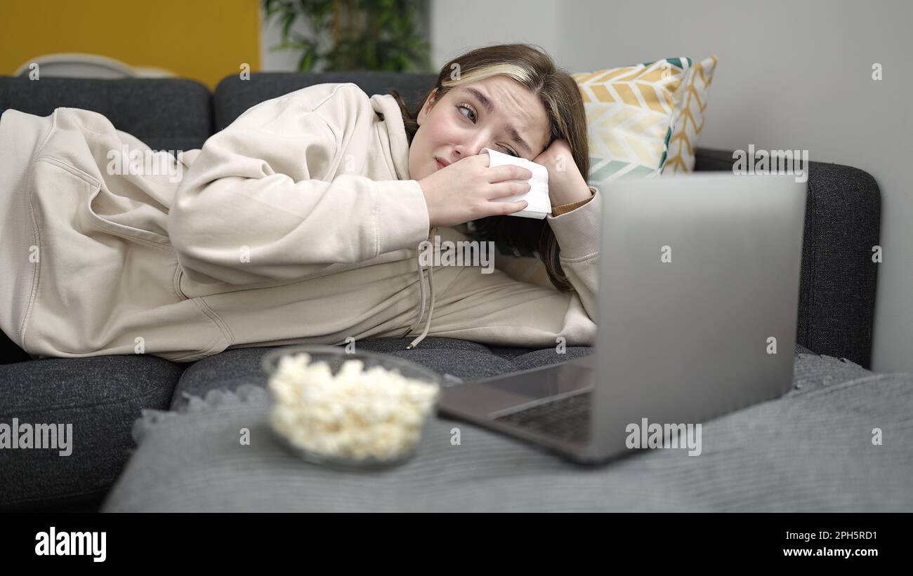 Young blonde woman watching movie crying on sofa at home Stock Photo ...