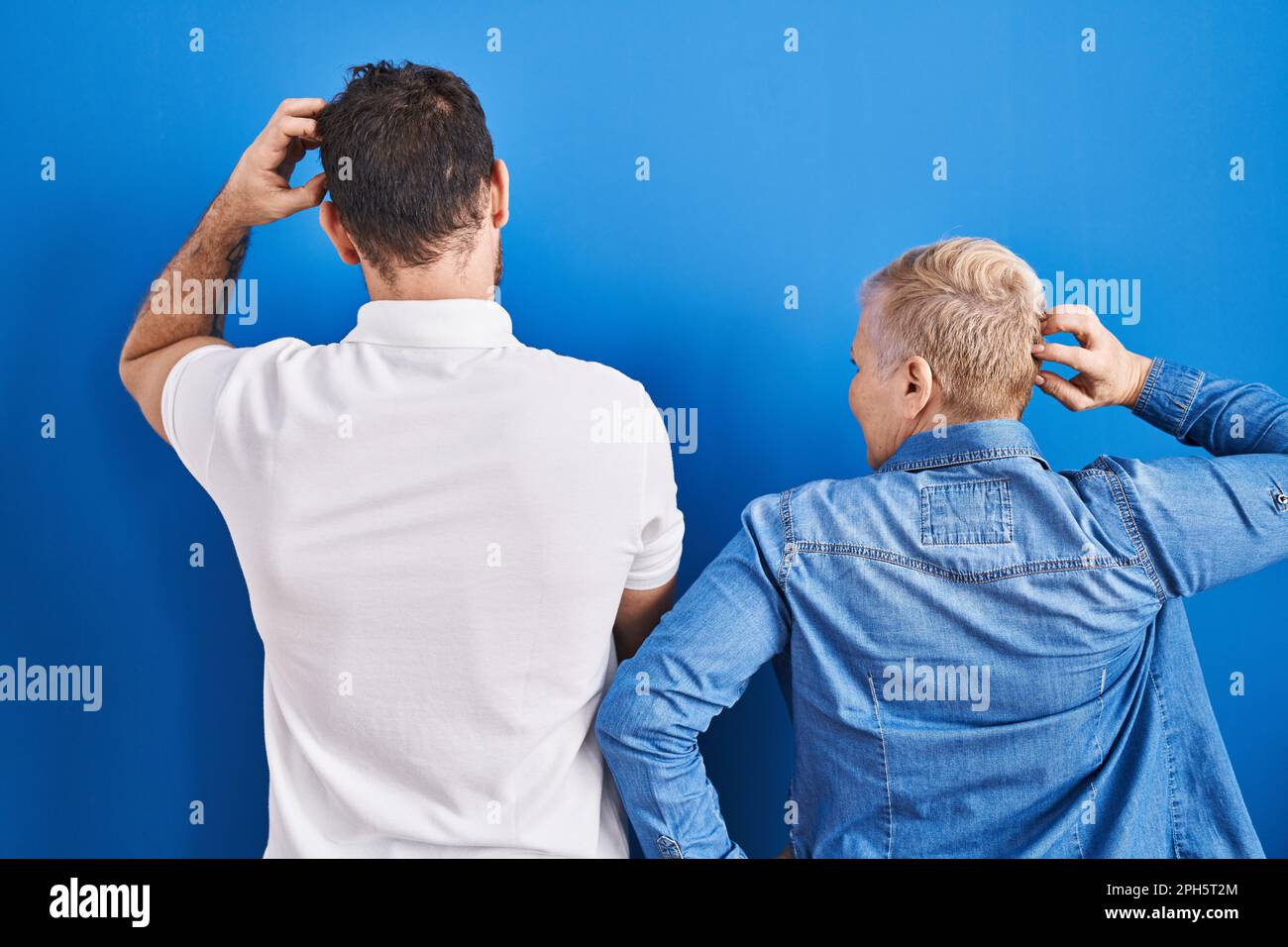 Young brazilian mother and son standing over blue background backwards ...