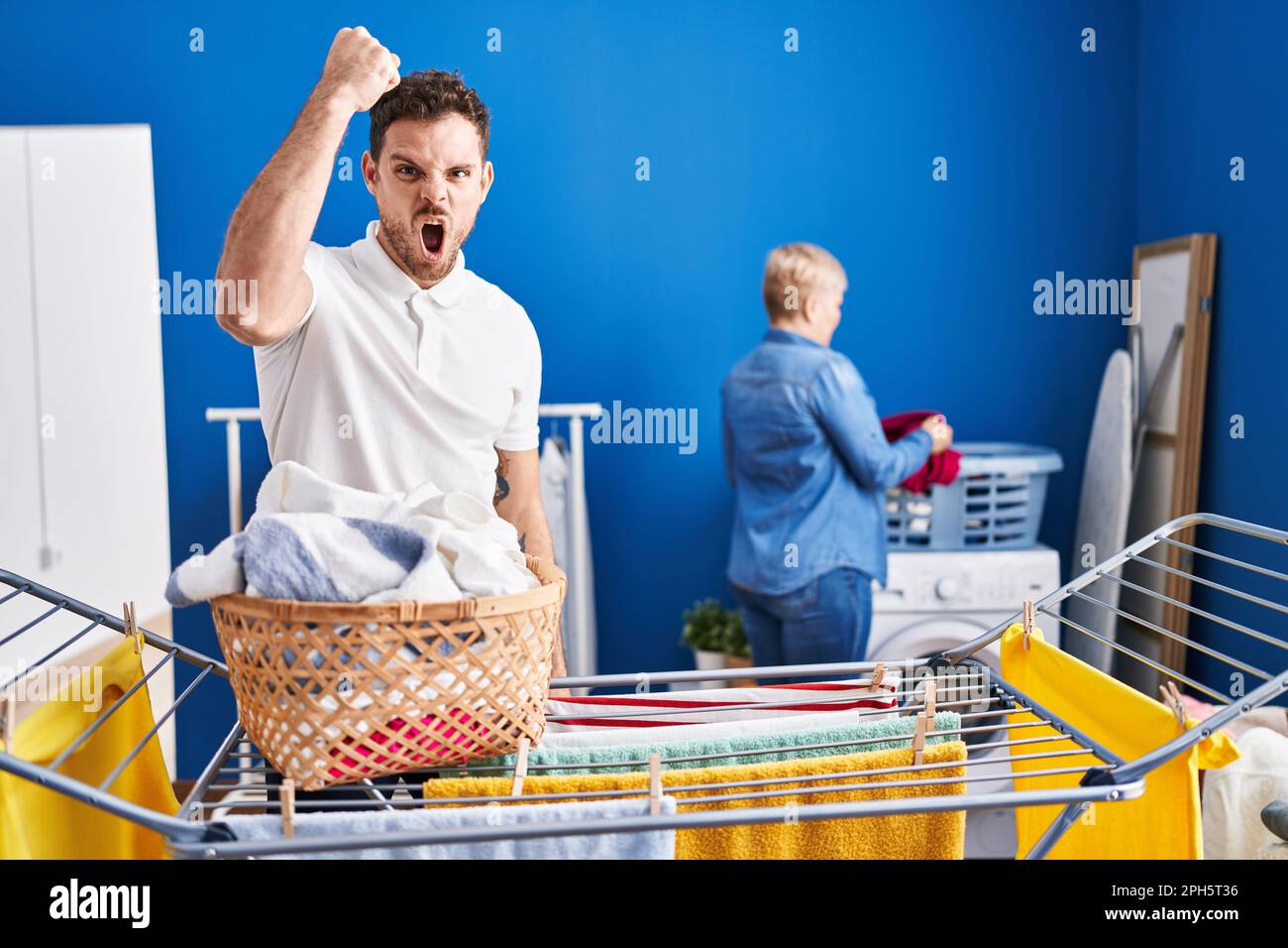Hispanic mother and son hanging clothes at clothesline annoyed and ...