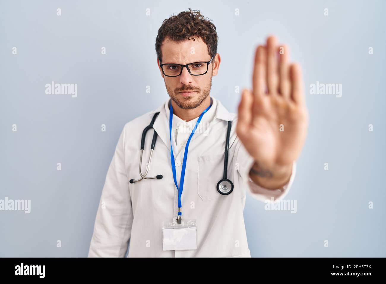 Young hispanic man wearing doctor uniform and stethoscope doing stop ...