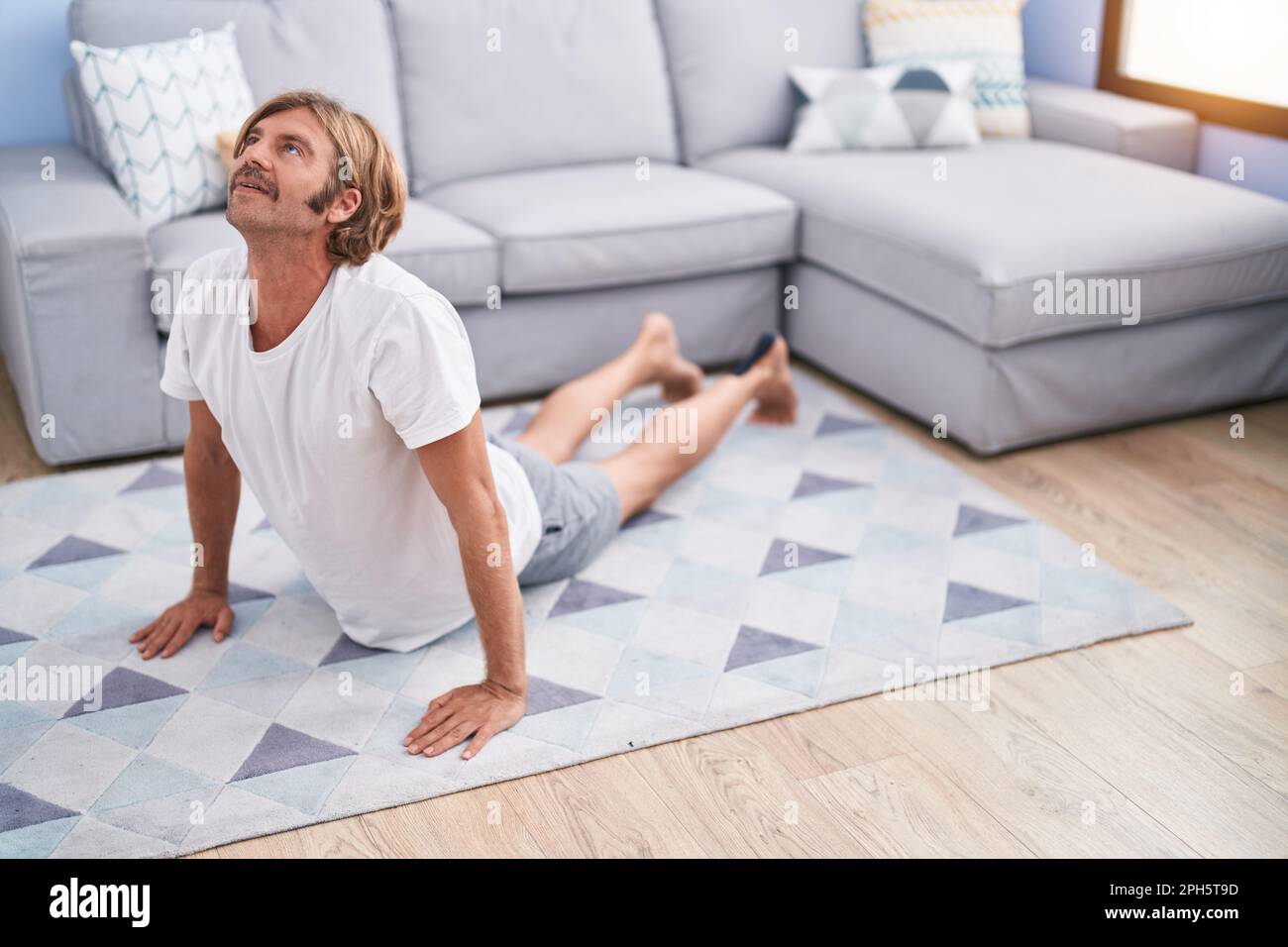 Young blond man stretching back at home Stock Photo - Alamy