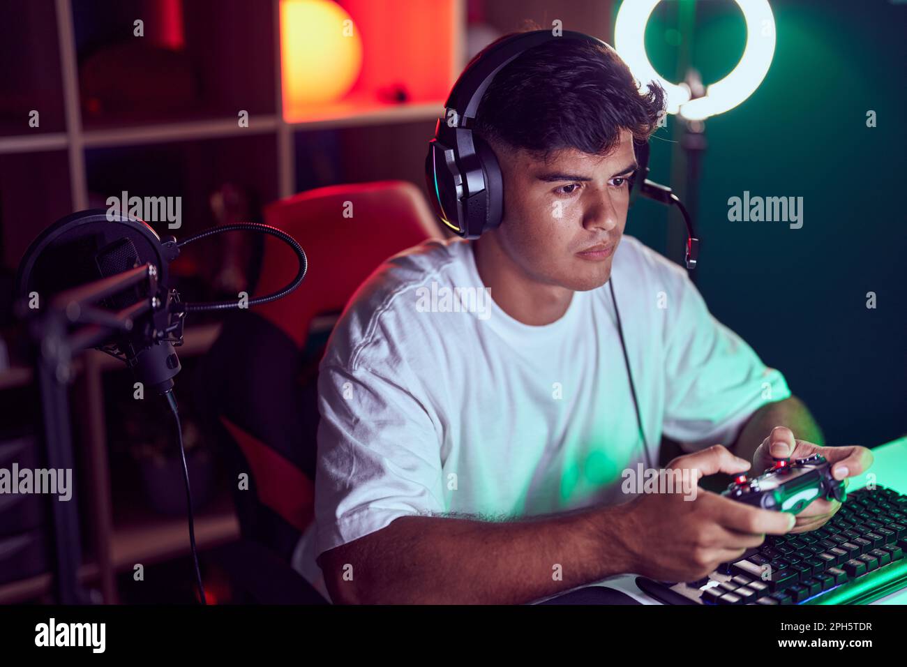 Young hispanic man streamer playing video game using joystick at gaming ...