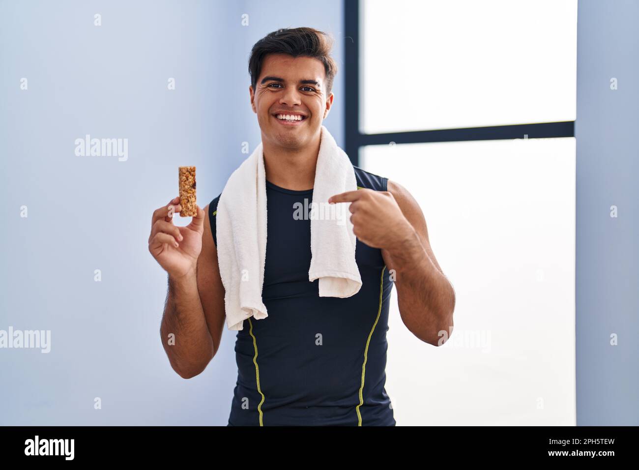 Hispanic man eating protein bar as healthy energy snack pointing finger ...