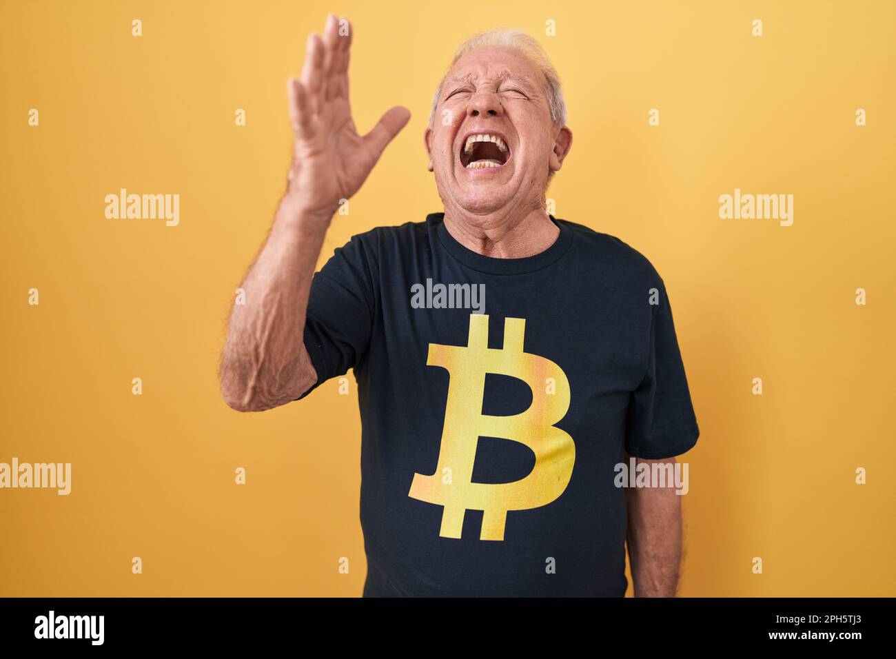 Senior man with grey hair wearing bitcoin t shirt crazy and mad ...