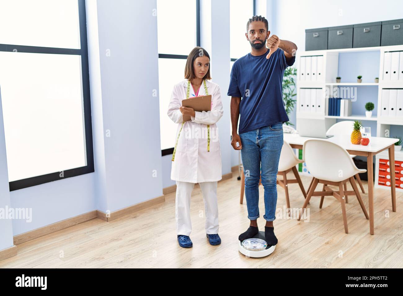 Dietitian at the clinic with client checking weight with angry face ...