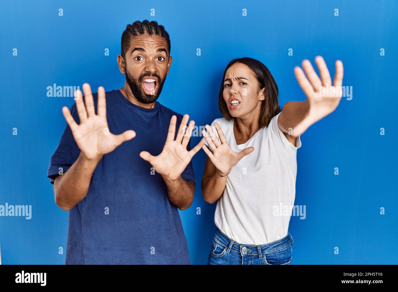 Young hispanic couple standing together afraid and terrified with fear ...