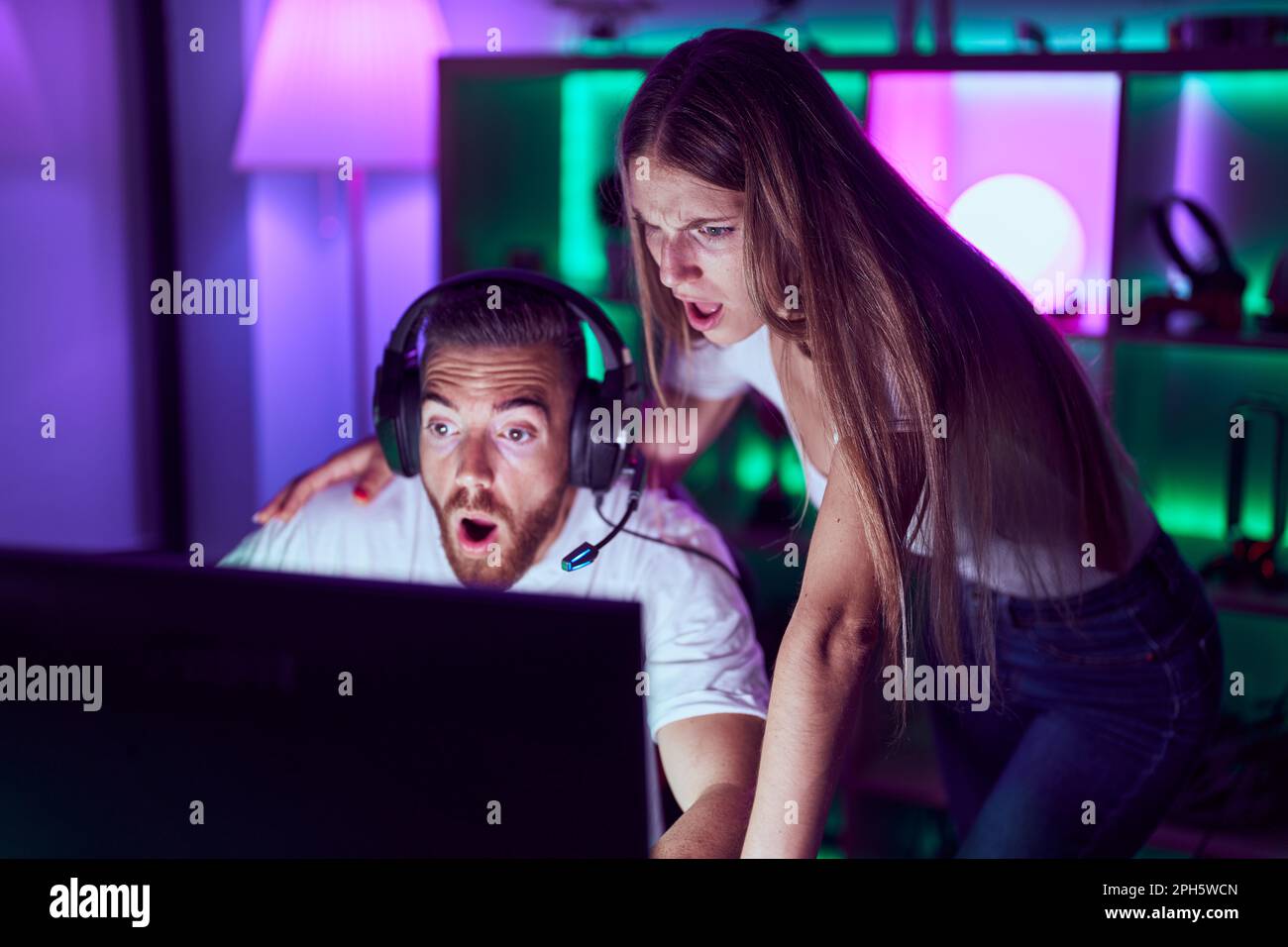 Young couple playing video games in shock face, looking skeptical and ...