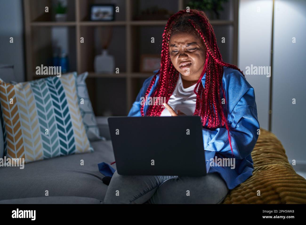 African american woman with braided hair using computer laptop at night ...
