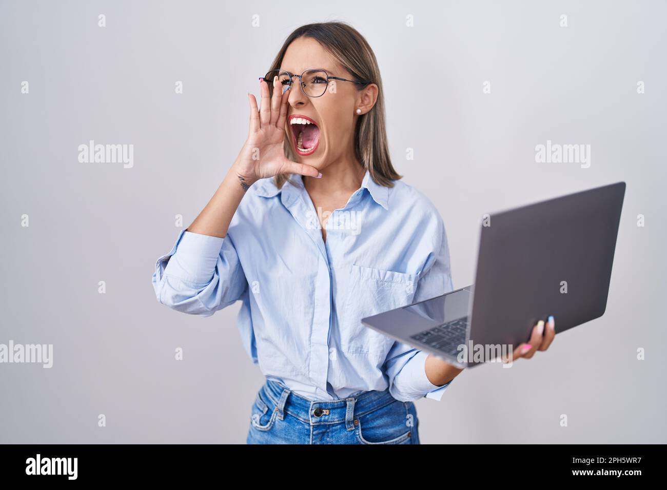 Young woman working using computer laptop shouting and screaming loud ...