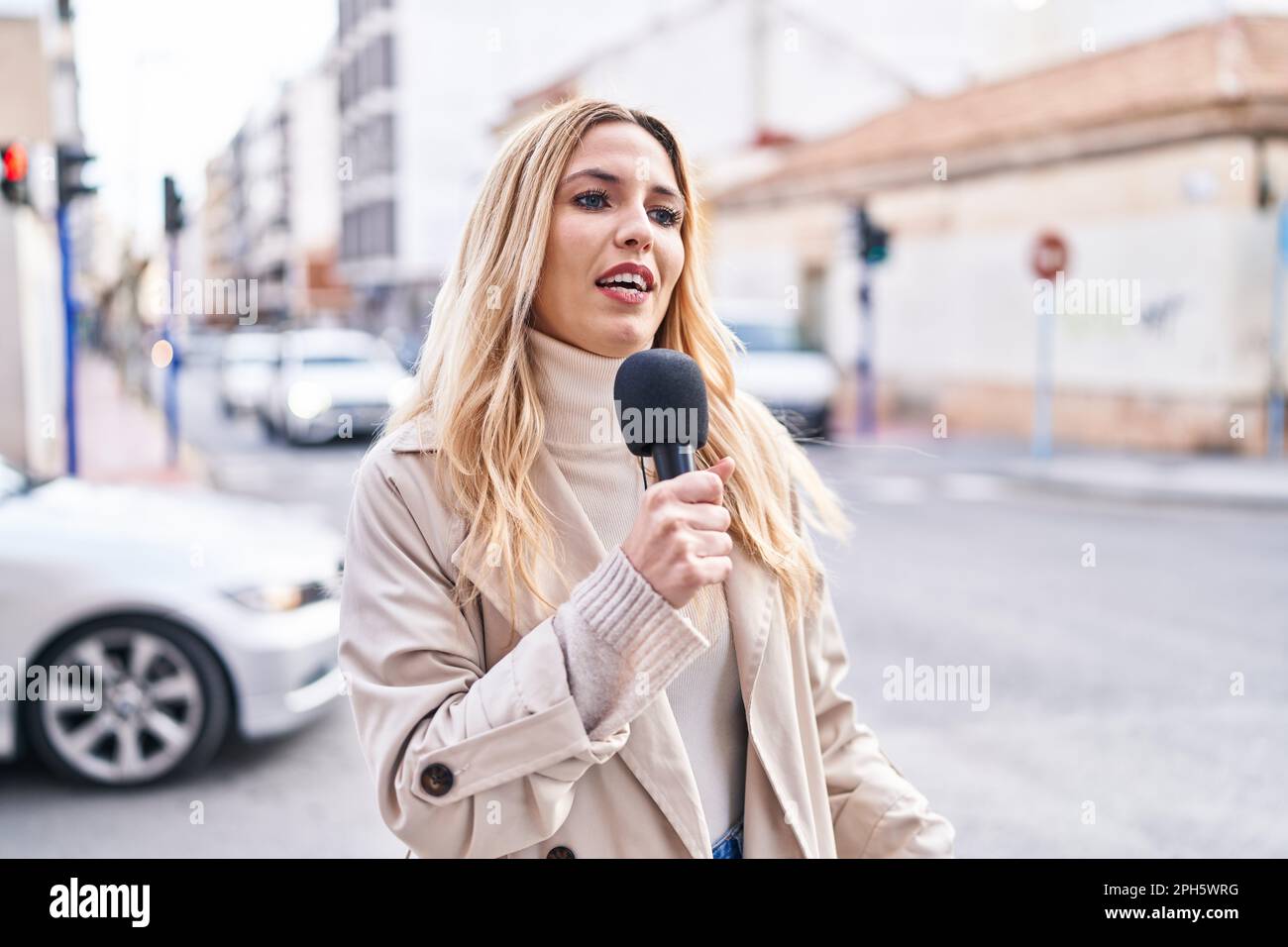 Young blonde woman reporter working using microphone at street Stock ...