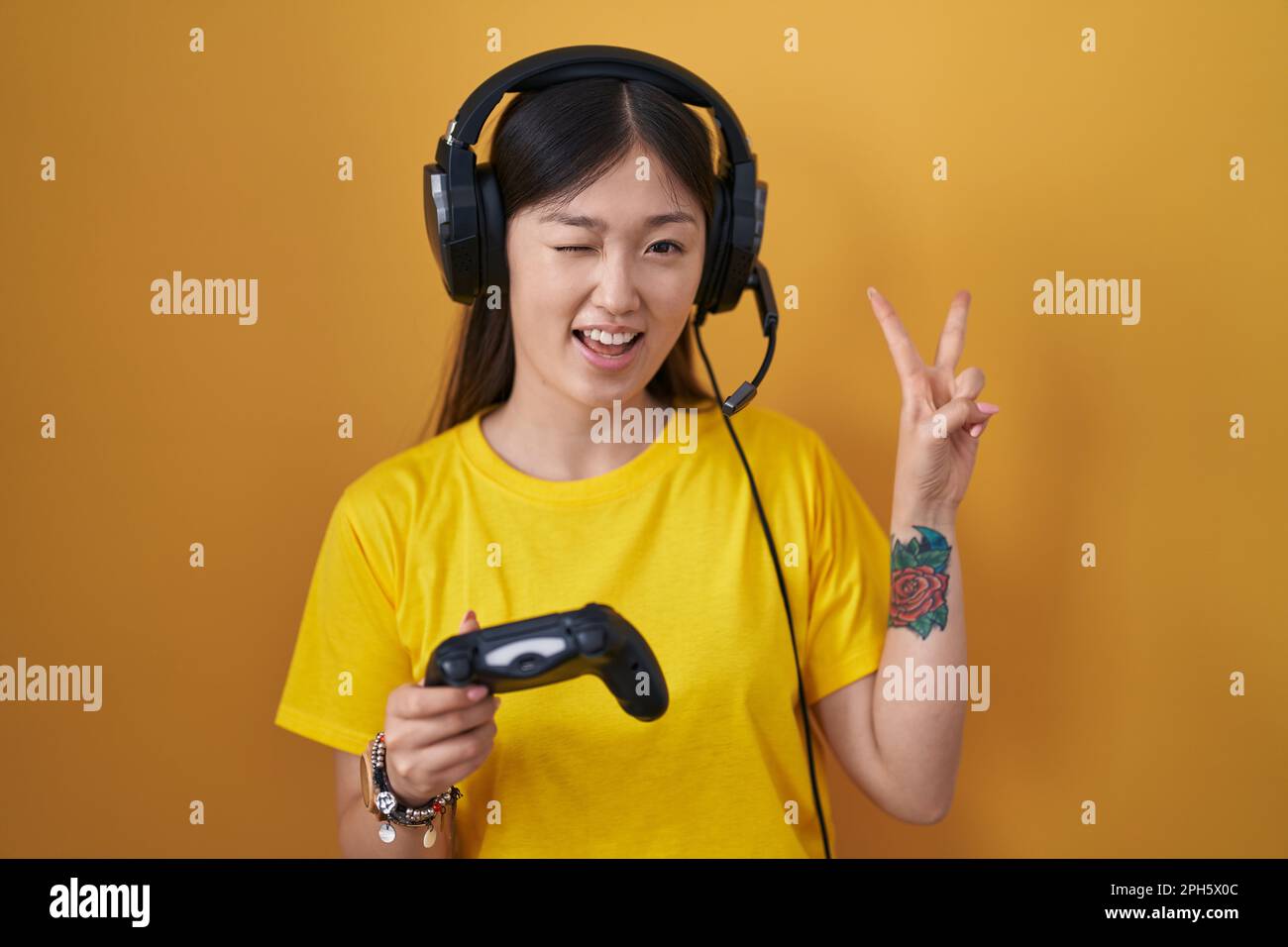 Chinese young woman playing video game holding controller smiling with ...