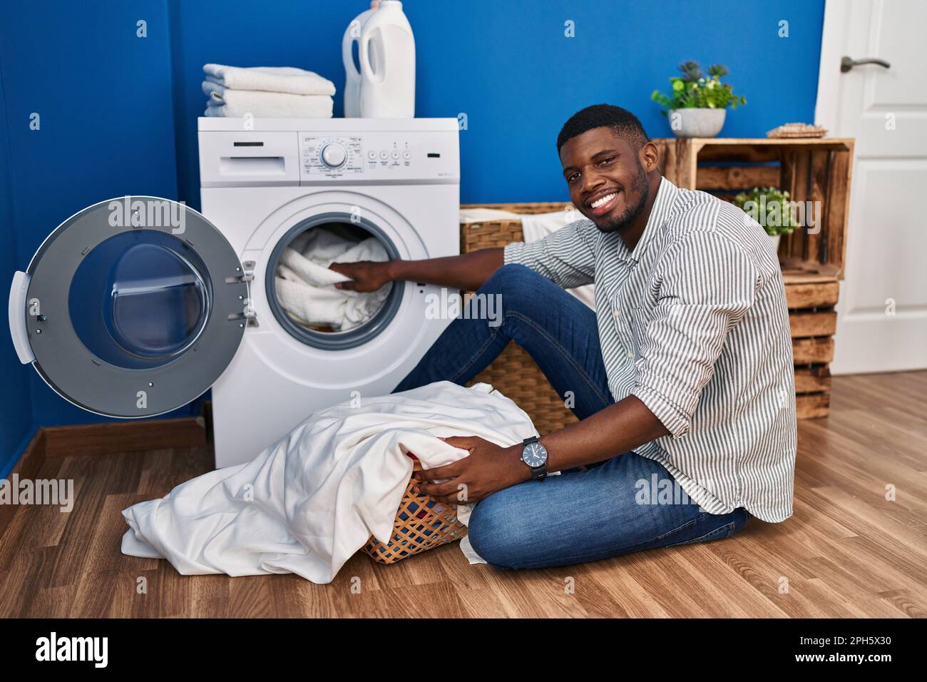 Young african american man smiling confident washing clothes at laundry ...
