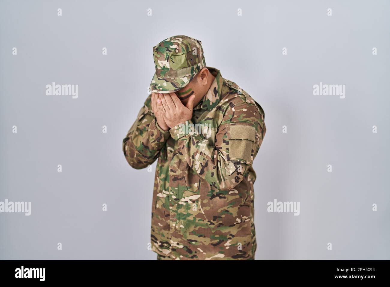 Hispanic young man wearing camouflage army uniform with sad expression ...