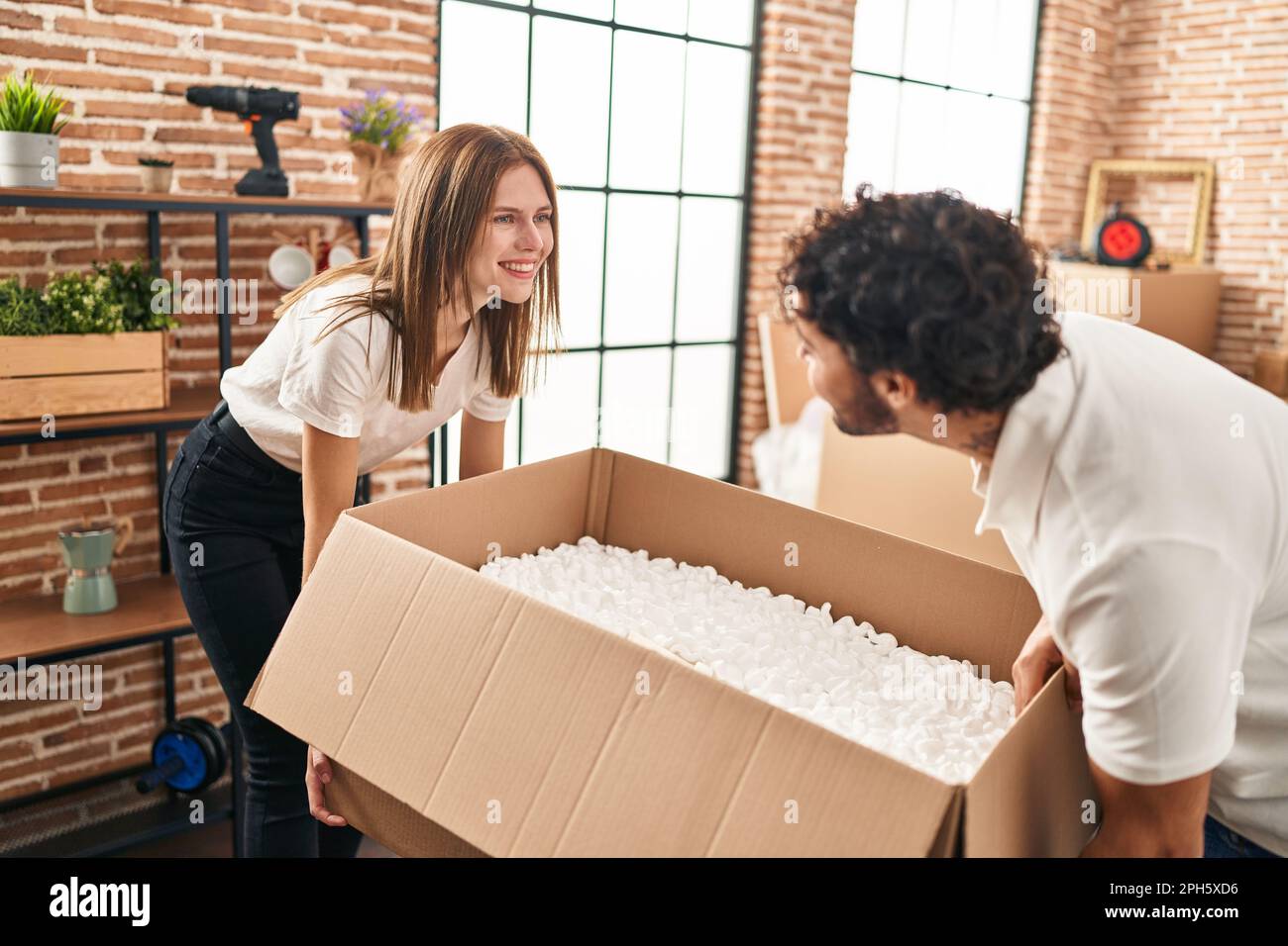 Man and woman couple smiling confident holding package at new home ...