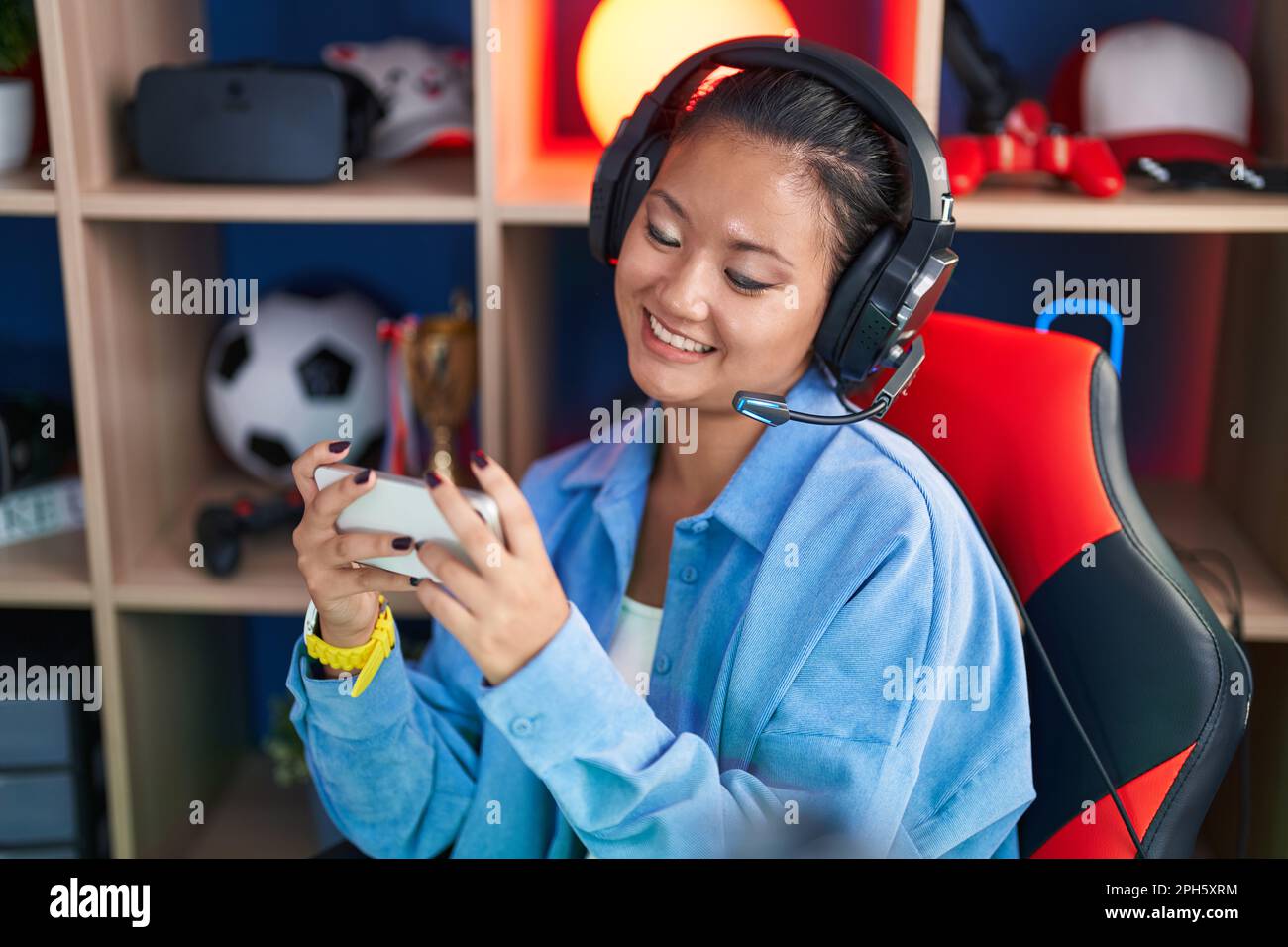 Young chinese woman streamer playing video game using smartphone at ...