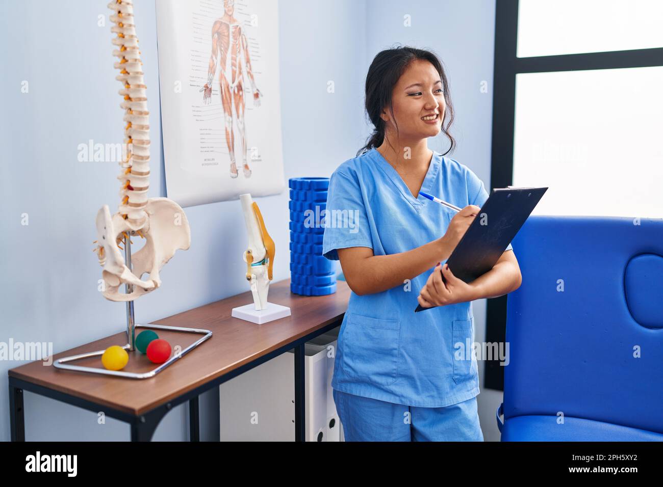 Young chinese woman wearing physiotherapist uniform write on medical ...