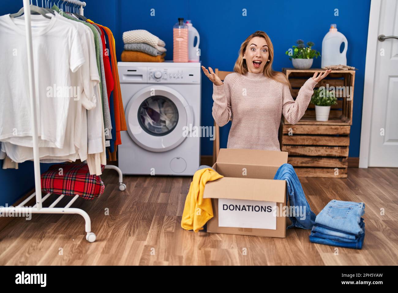 Hispanic woman putting clothes in donation box celebrating victory with ...