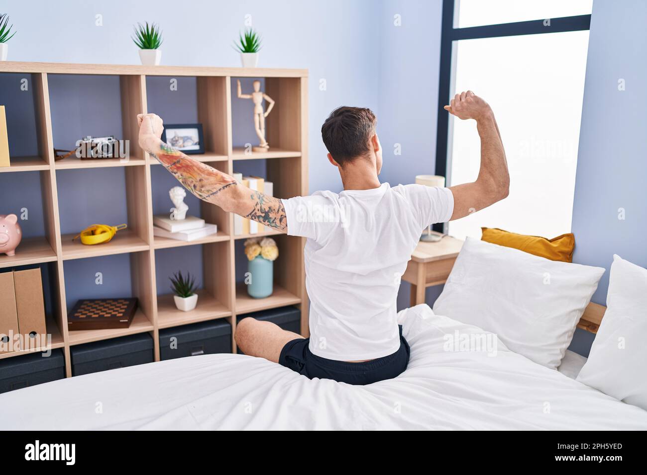 Young man waking up stretching arms on back view at bedroom Stock Photo ...
