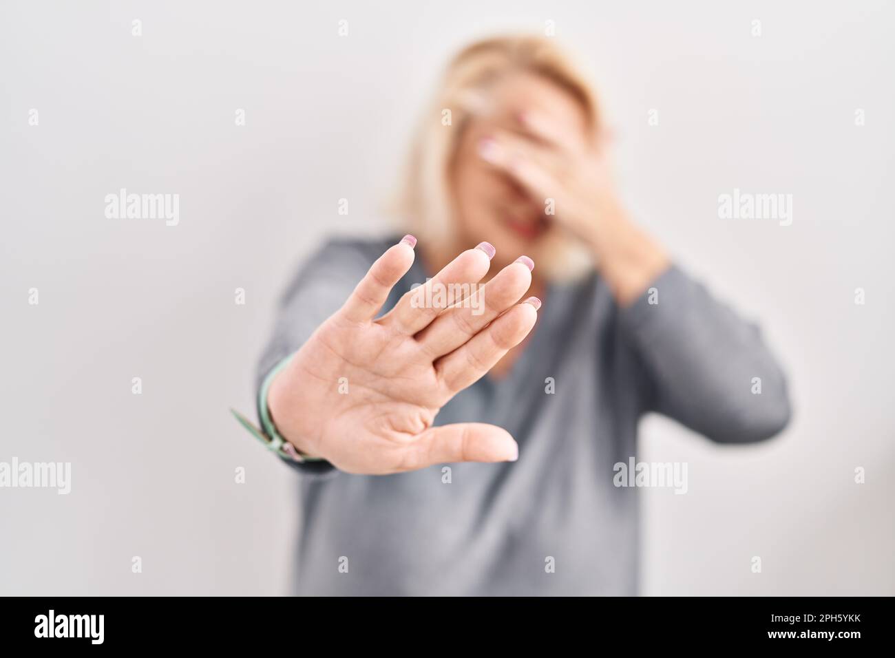 Middle age caucasian woman standing over white background covering eyes ...