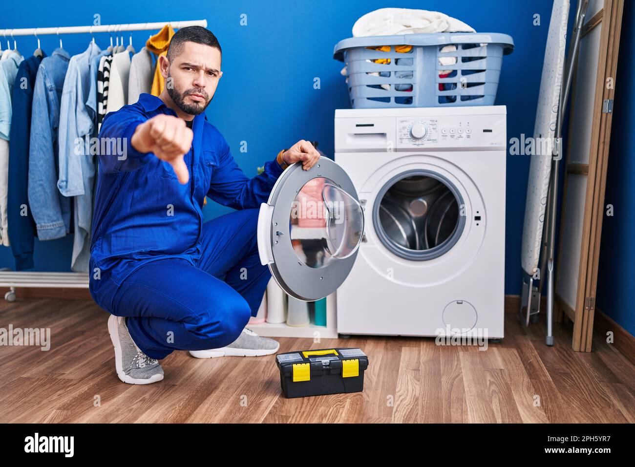 Hispanic repairman working on washing machine with angry face, negative ...
