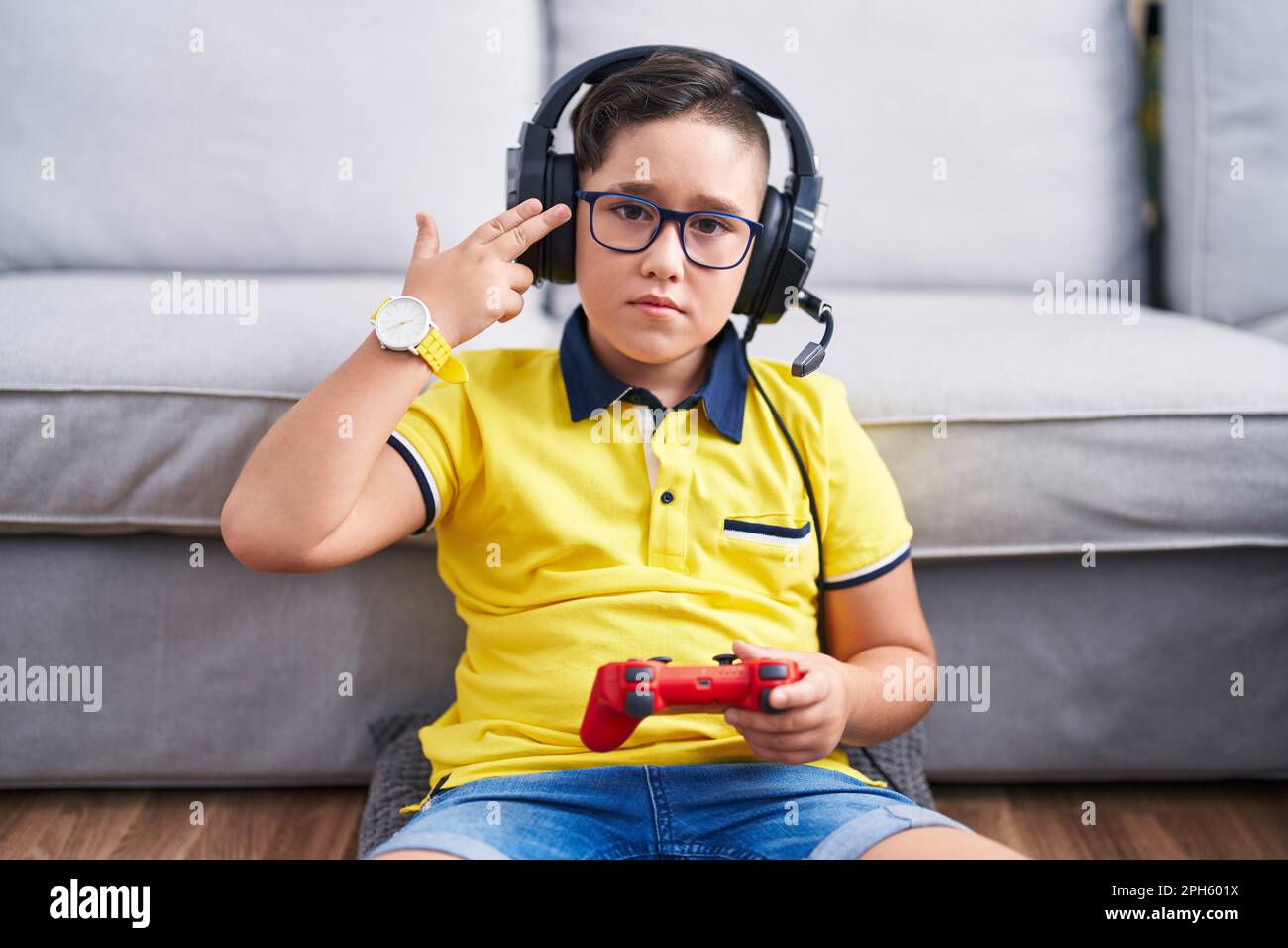 Young hispanic kid playing video game holding controller wearing ...