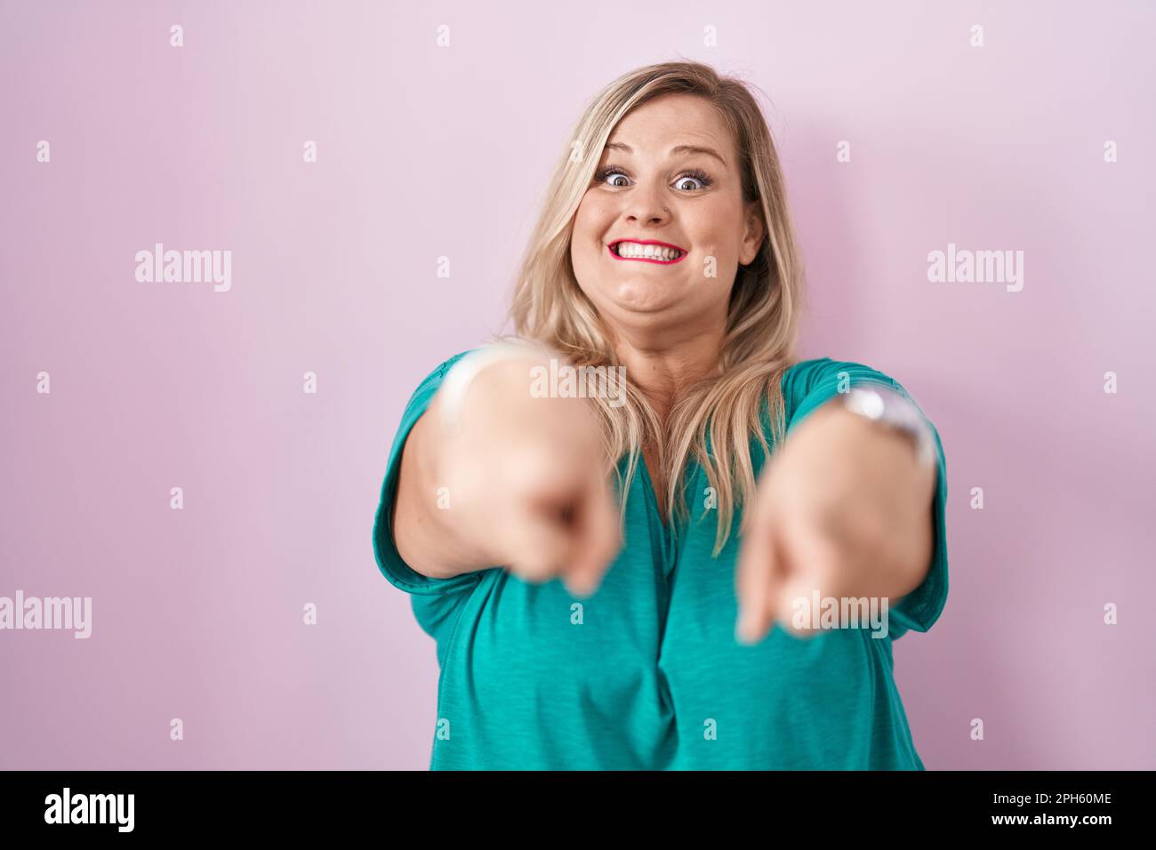 Caucasian plus size woman standing over pink background pointing to you ...
