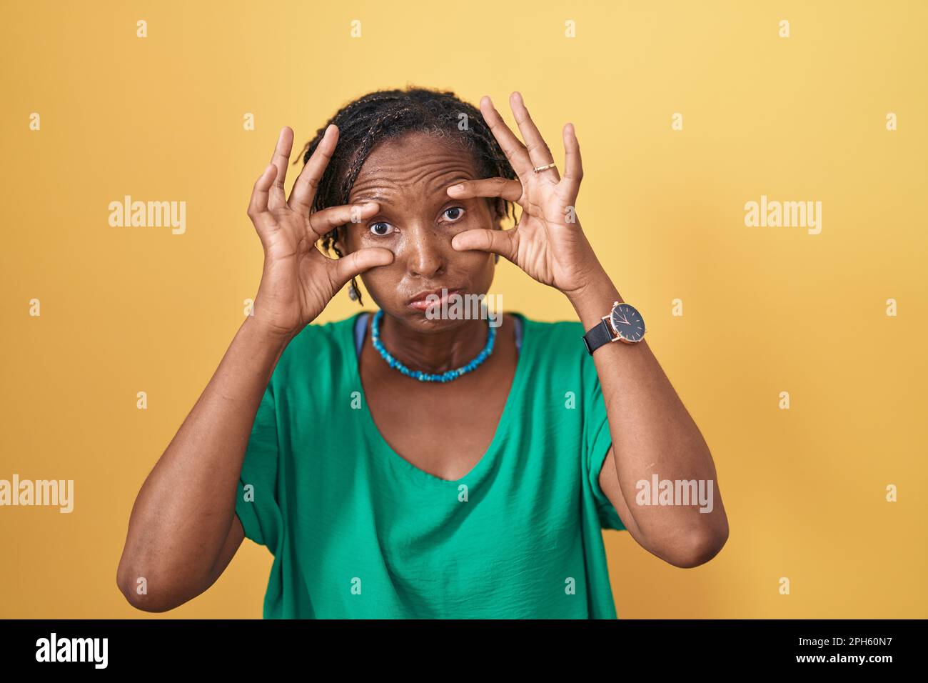 African woman with dreadlocks standing over yellow background trying to ...