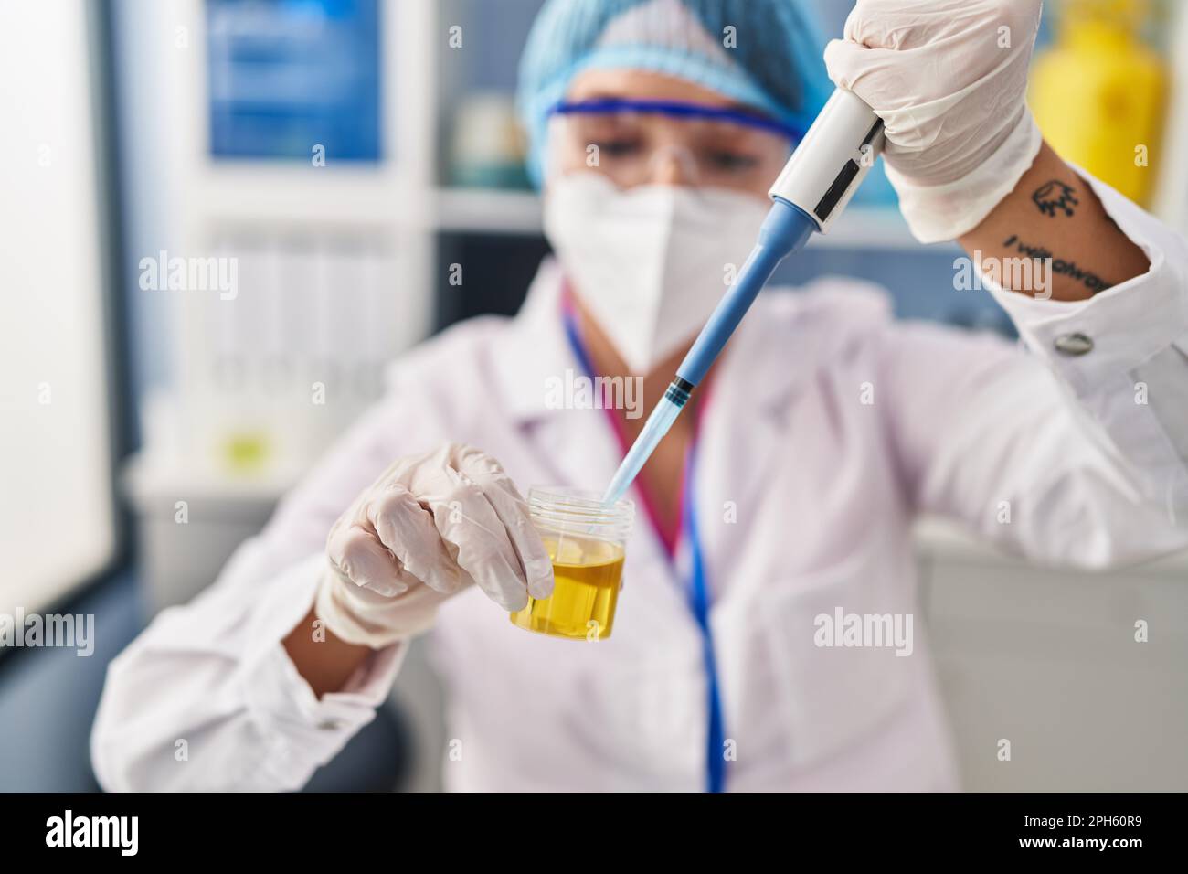 Young beautiful hispanic woman scientist pouring liquid to urine test ...