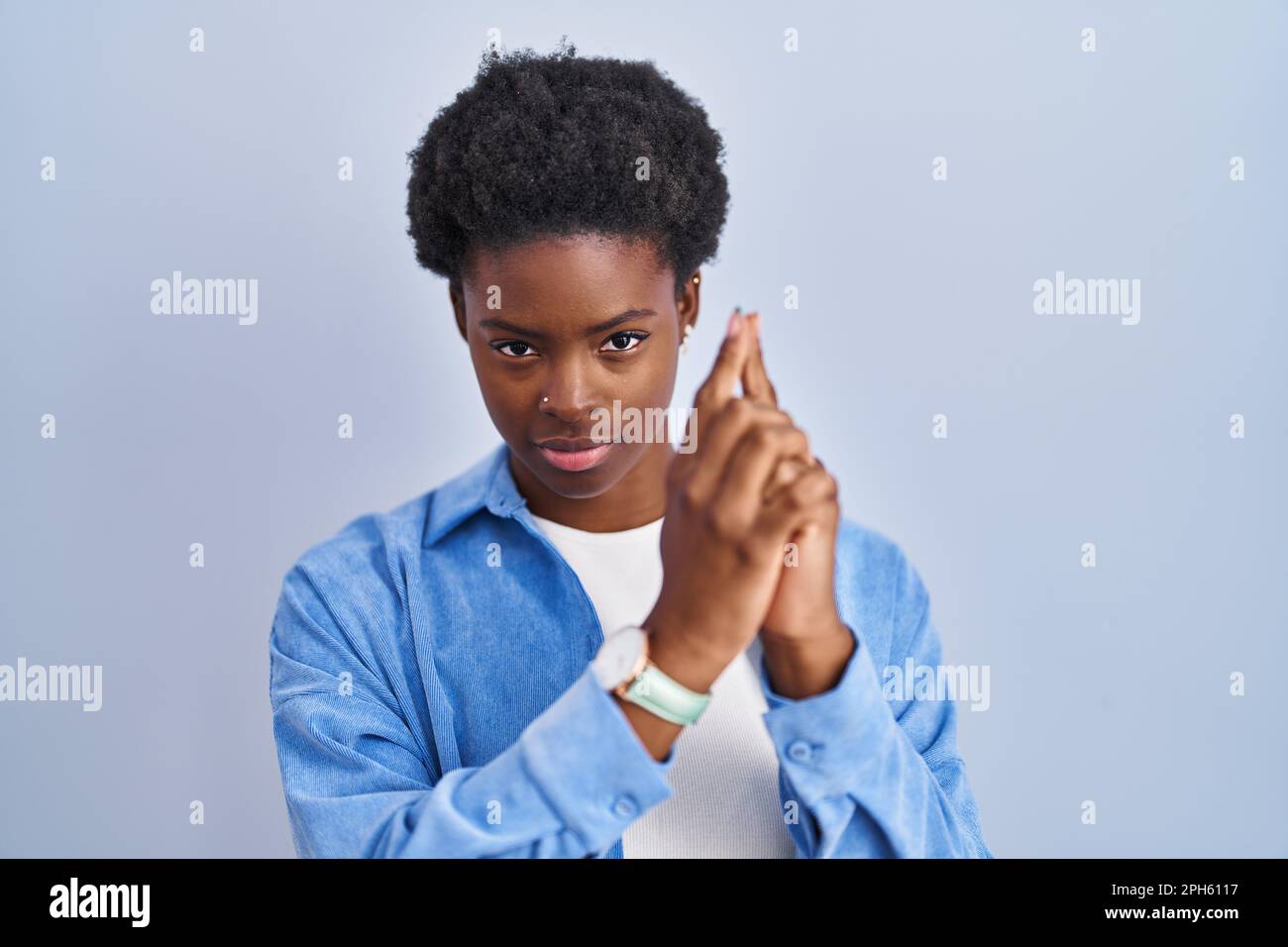 African american woman standing over blue background holding symbolic ...