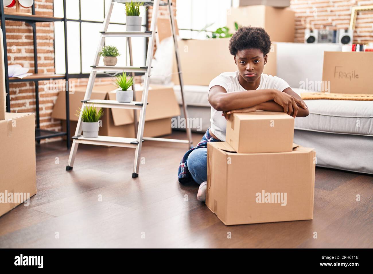 African american woman sitting on the floor at new home depressed and ...