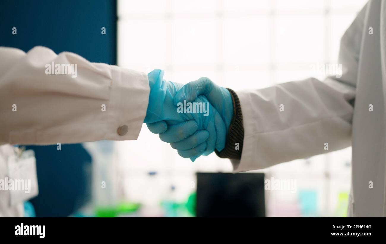 Man and woman wearing scientist uniform shake hands at laboratory Stock ...
