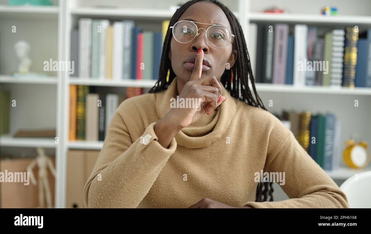 African woman reading a book asking for silence at library university ...