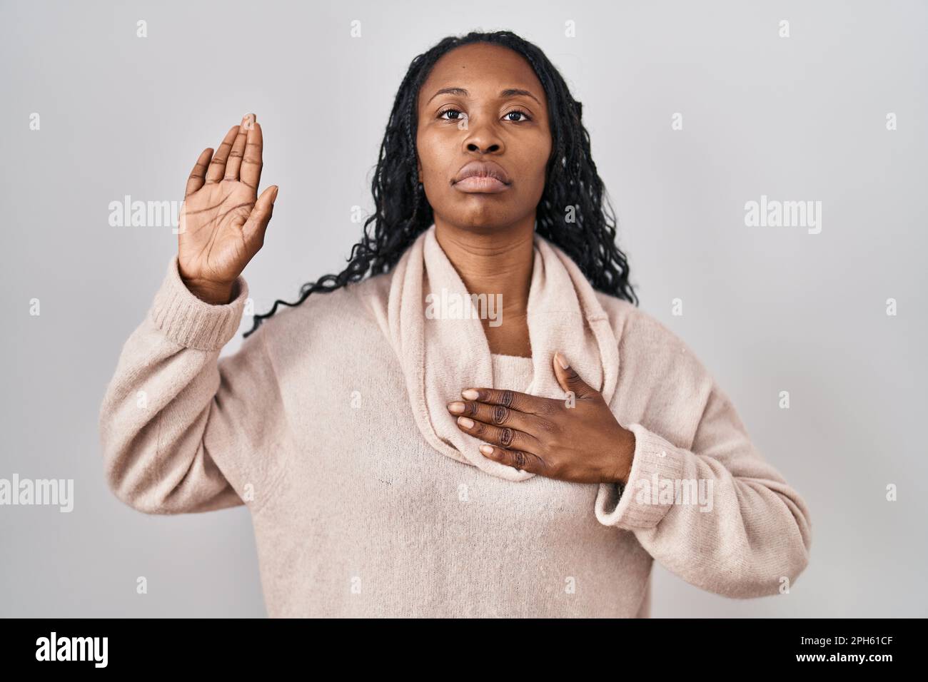 African woman standing over white background swearing with hand on ...