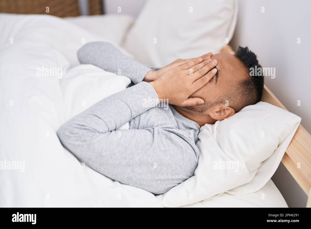Young hispanic man lying on bed crying at bedroom Stock Photo - Alamy