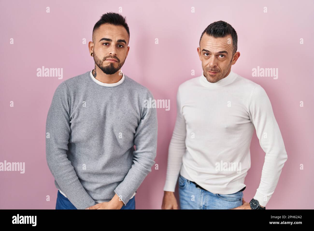 Homosexual couple standing over pink background depressed and worry for ...