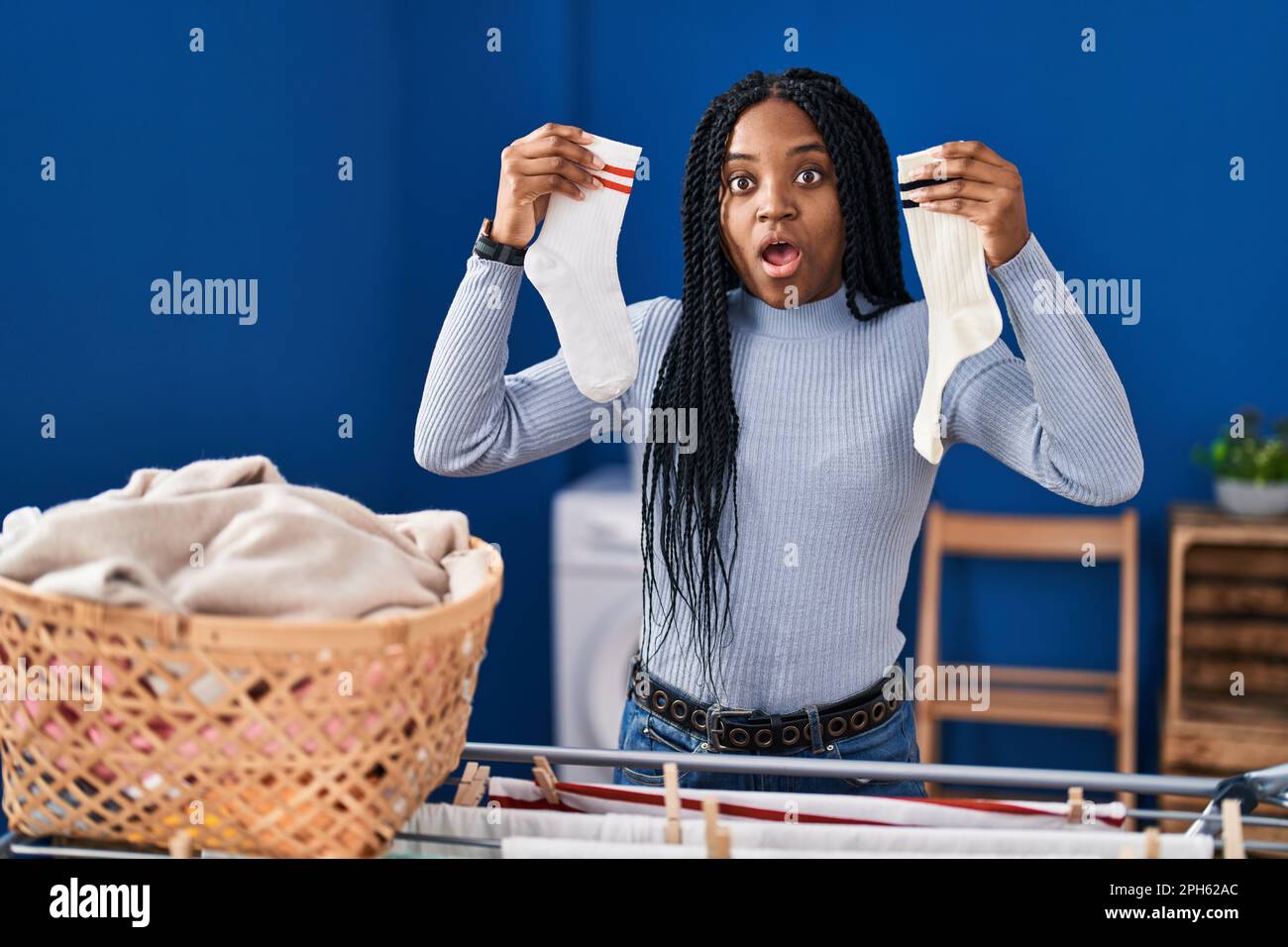 African american woman holding socks in shock face, looking skeptical ...