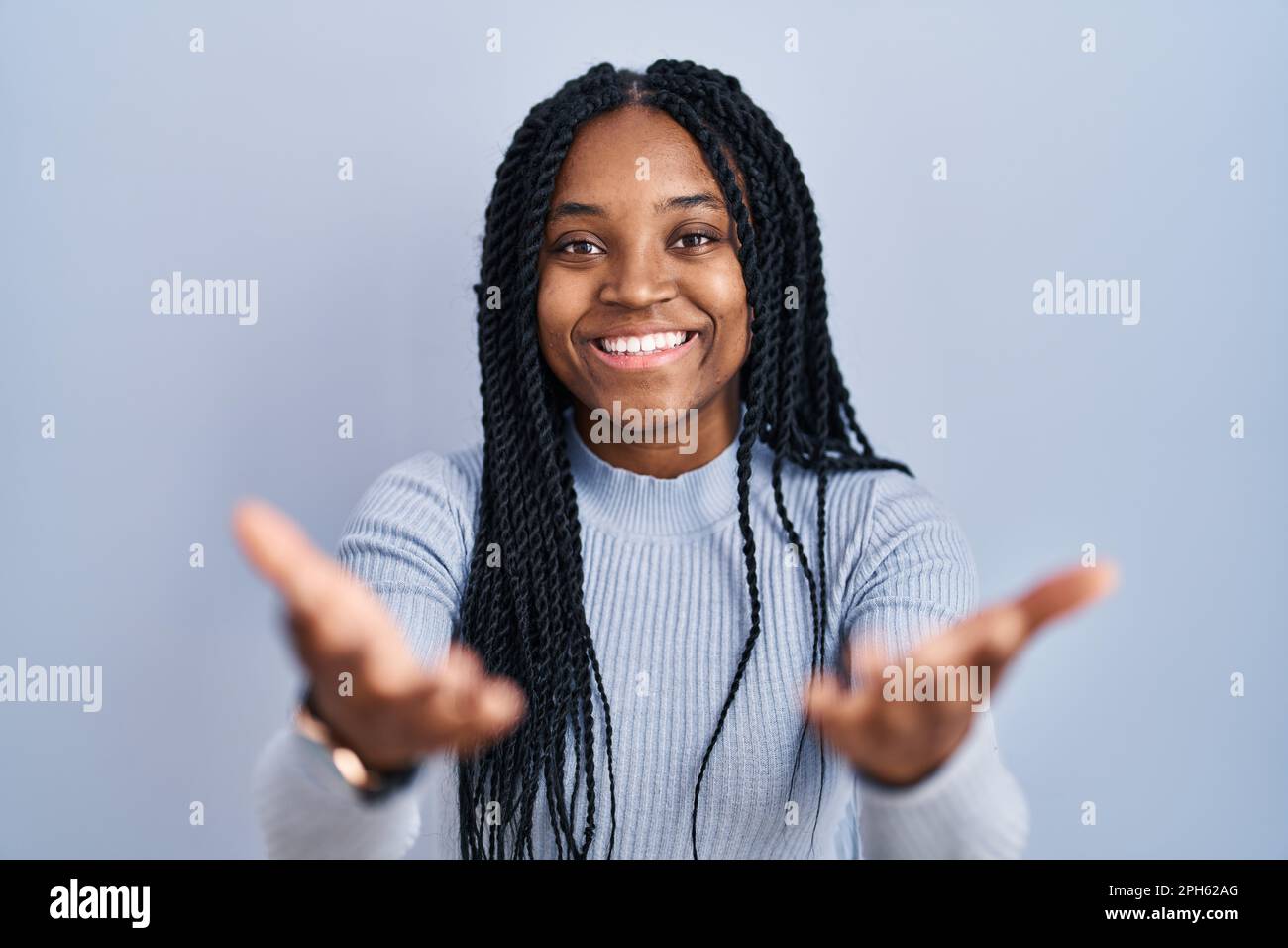 African american woman standing over blue background smiling cheerful ...