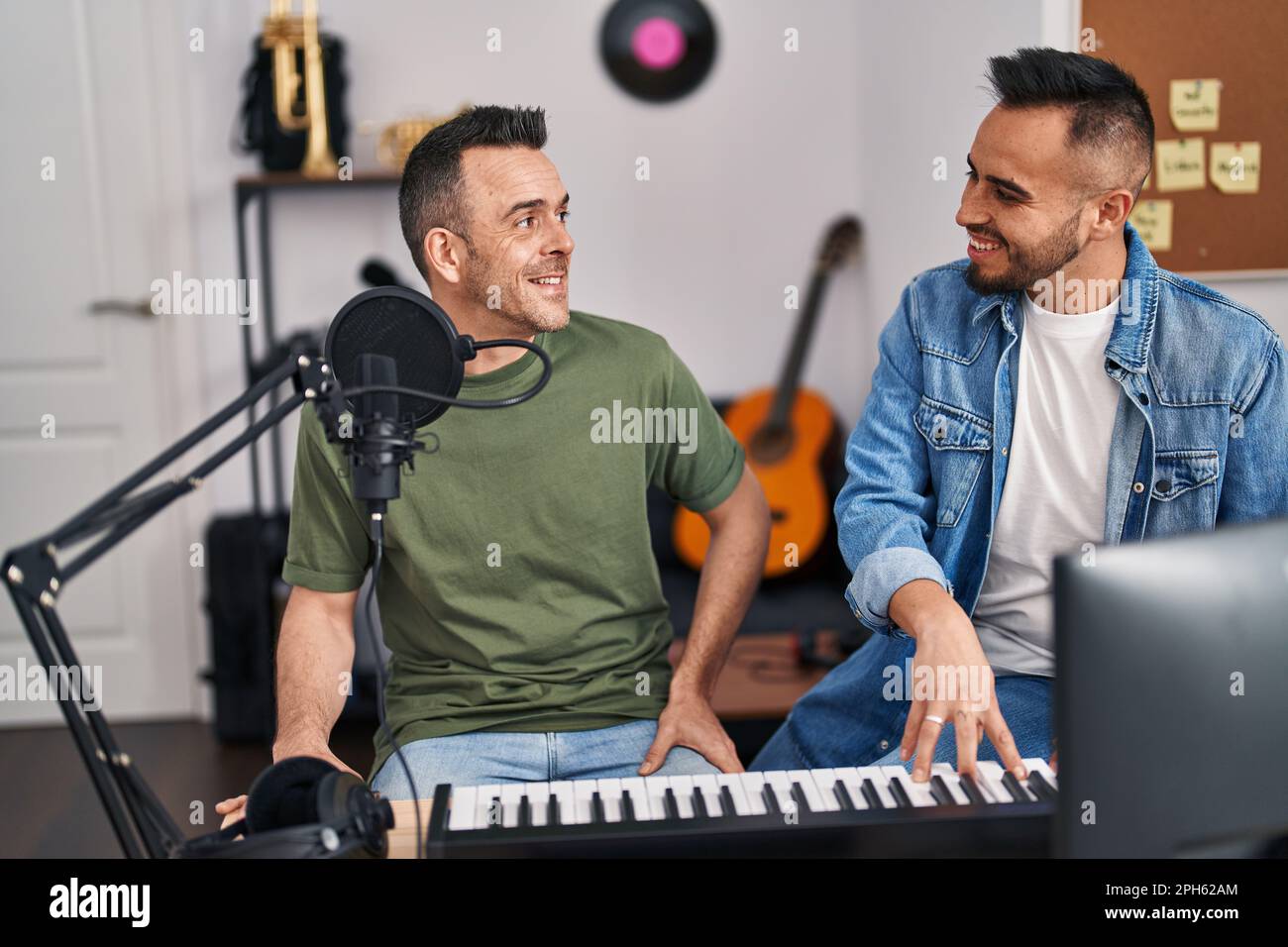 Two men musicians singing song playing piano at music studio Stock ...