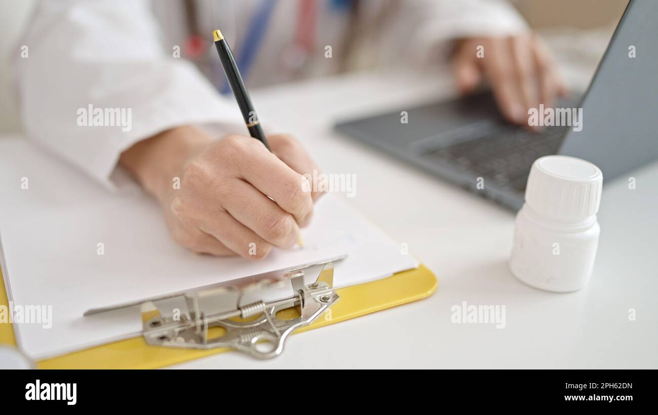 Young beautiful hispanic woman doctor using laptop writing medical ...