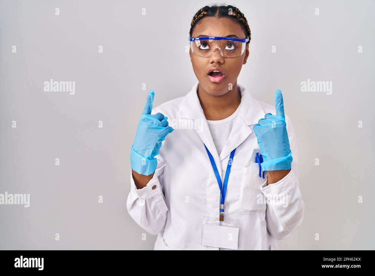 African american woman with braids wearing scientist robe amazed and ...