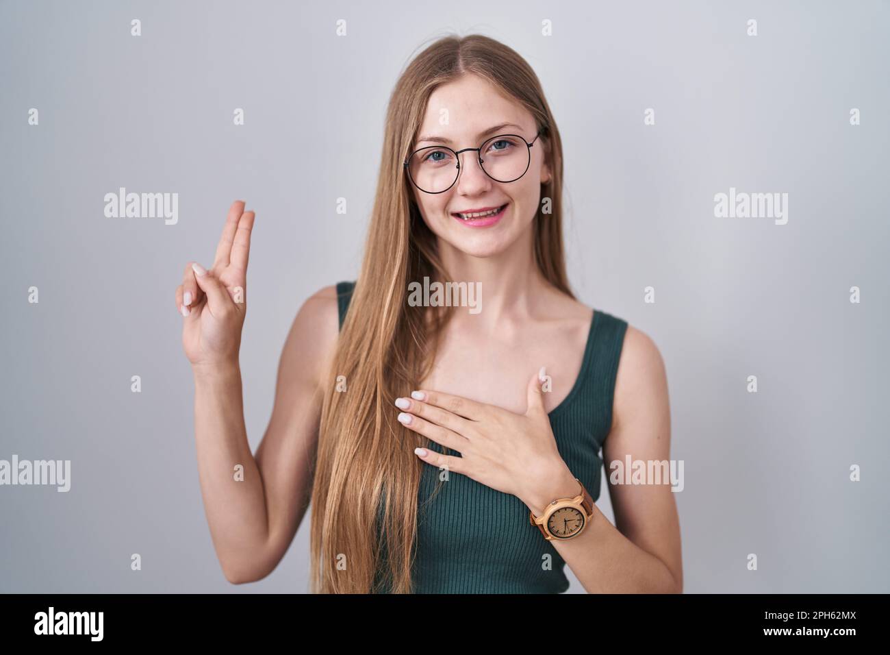 Young caucasian woman standing over white background smiling swearing ...