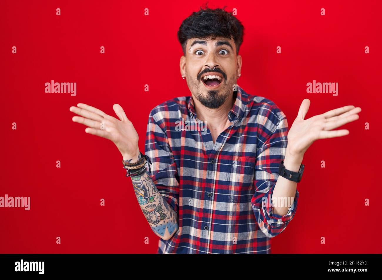 Young hispanic man with beard standing over red background celebrating ...
