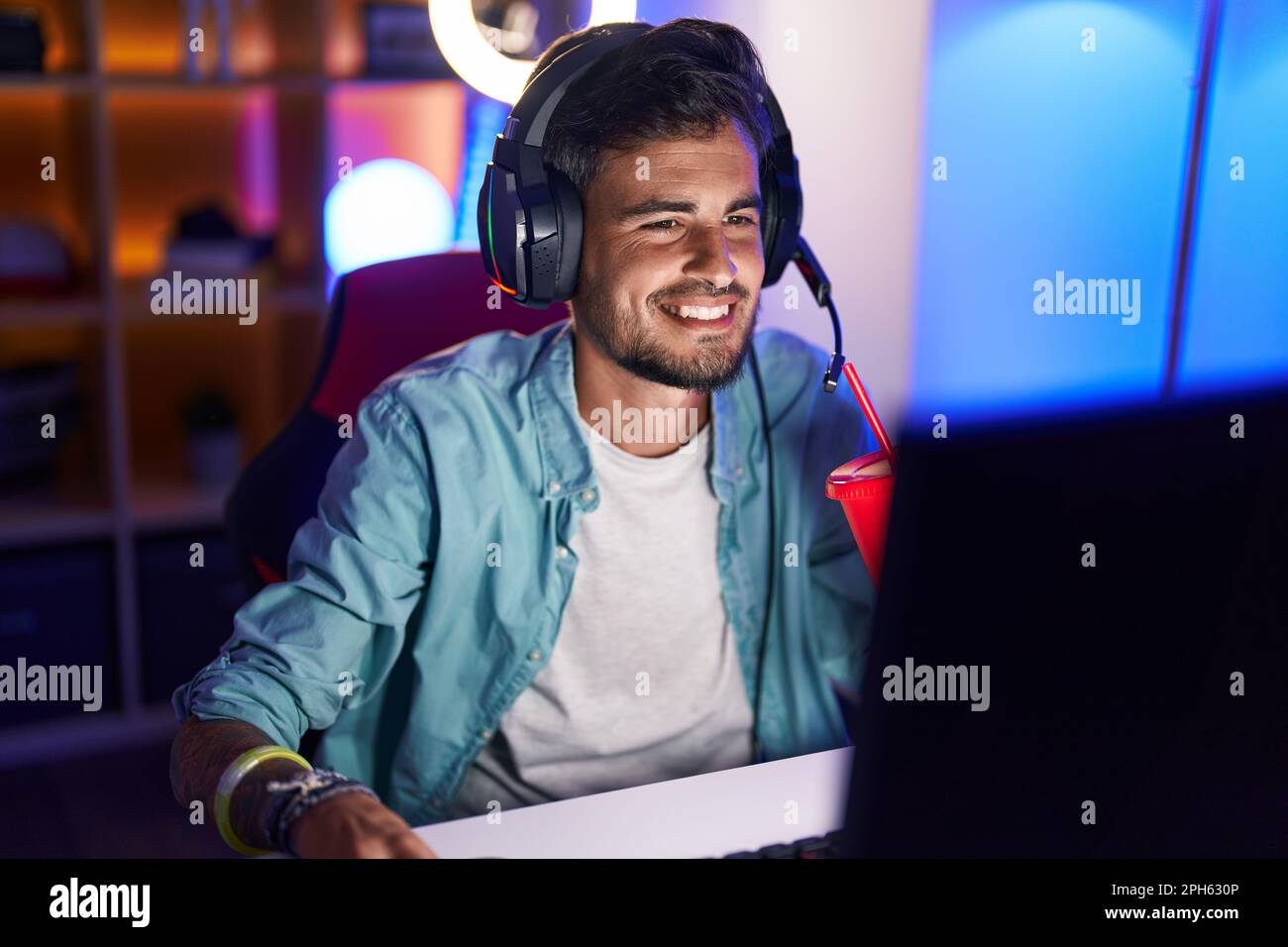 Young hispanic man streamer playing video game using computer at gaming ...