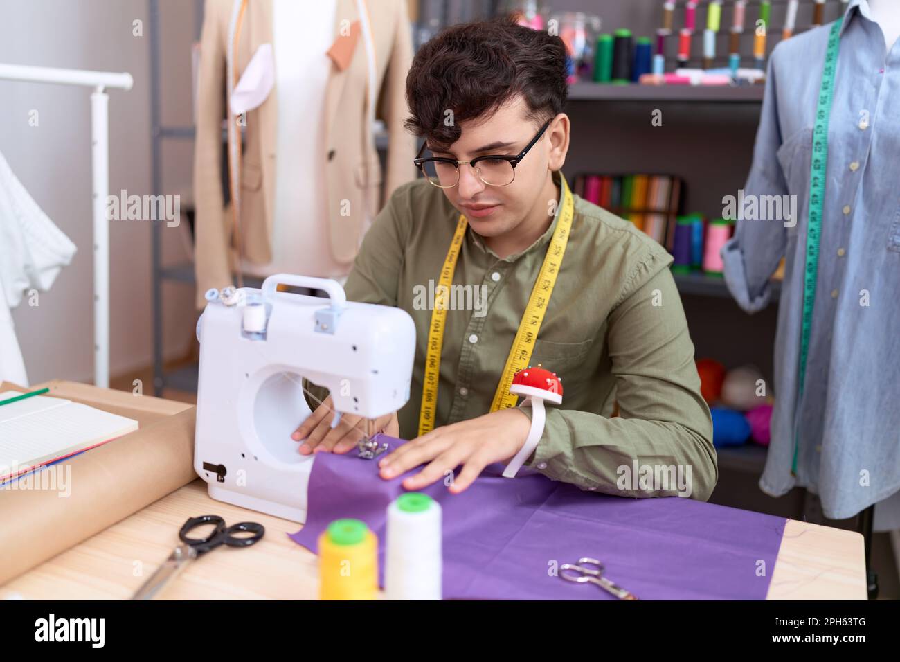 Non binary man tailor using sewing machine at atelier Stock Photo - Alamy
